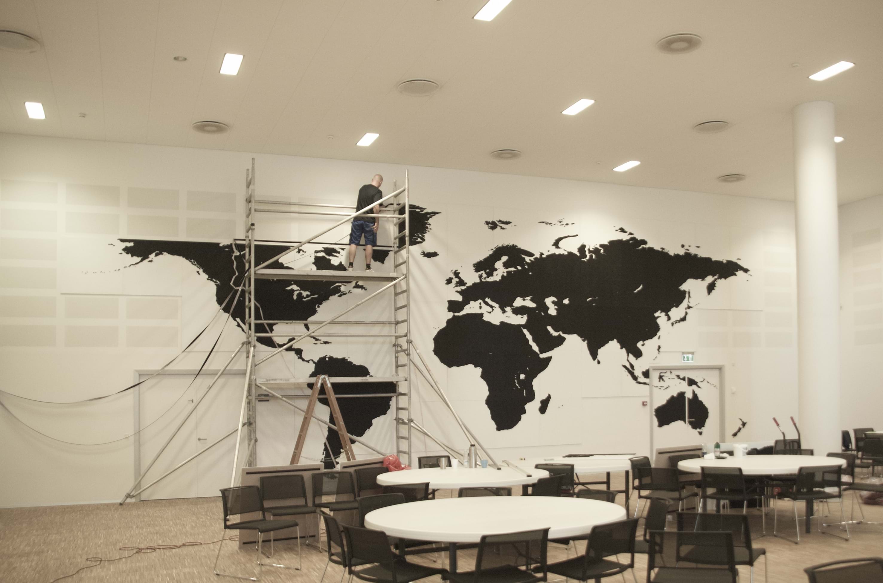 Et stort verdenskort af filt. Flot installation i konference rum